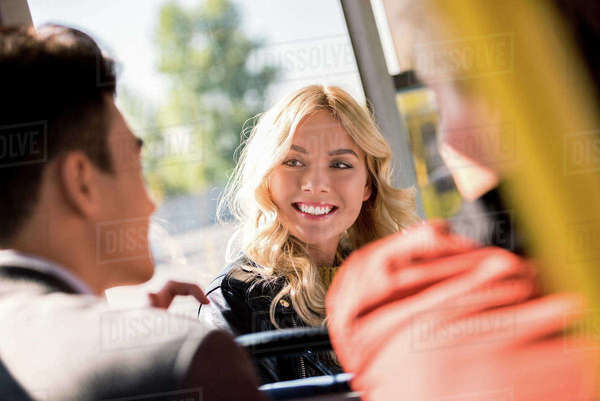 Selective Focus Of Smiling Young Woman Talking With Friends In Public selective-focus-of-smiling-young-woman-talking-with-friends-in-public