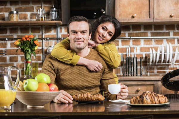 Happy Young Multiethnic Couple Embracing And Smiling At Camera While