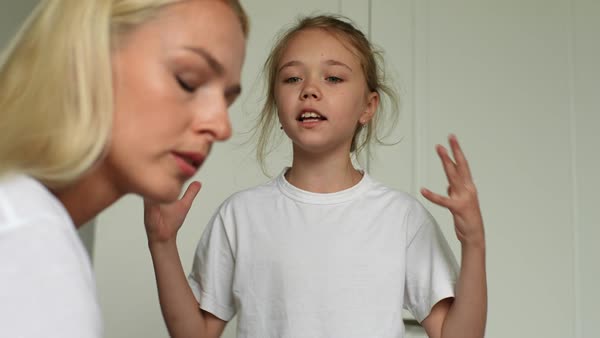 Close-up face of angry cute little child daughter scolding, raising voice, shouting and ...