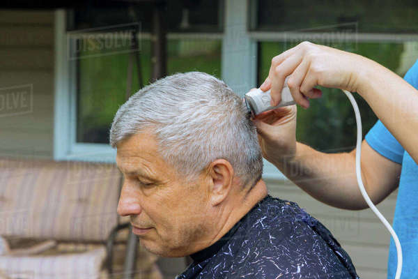Professional barber with man getting haircut while sitting in chair at home outside - Royalty ...