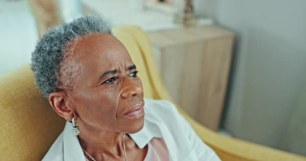 Thinking, nostalgia and sad senior black woman in a chair with memory or depression at nursing ...