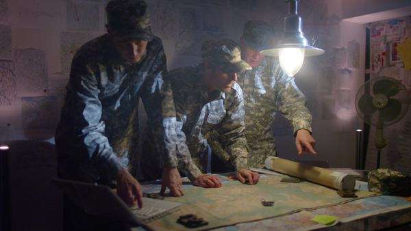 Military officers in army bunker, looking at a map and discussing ... Military officers in army bunker, looking at a map and discussing ...