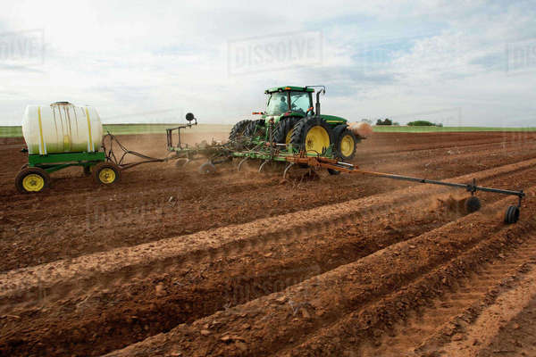 Agriculture - John Deere tractor pulling a field implement preparing a field for planting cotton ...