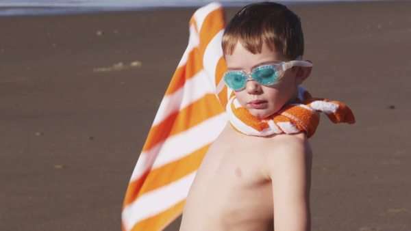 Young boy at beach flexing muscles with superhero costume - Stock Video ...