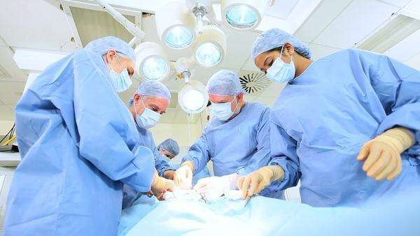 Doctor wearing protective clothing performing surgery using sterilized ...
