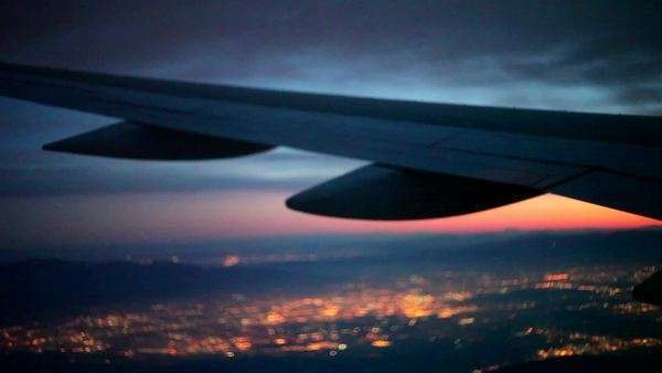View of airplane wing while flying over city lights at sunset - HD ...