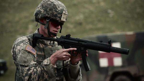Stationary shot of a soldier shooting a submachine gun that looks to be ...