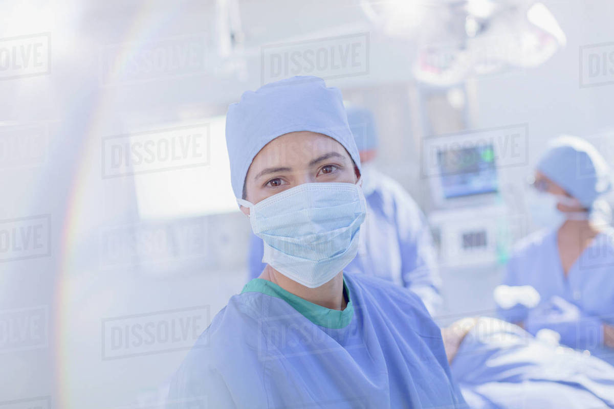 Portrait confident female surgeon wearing surgical mask in operating ...