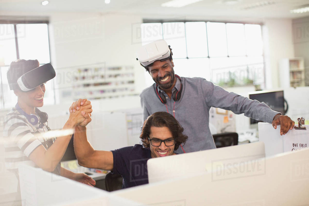 Smiling, enthusiastic computer programmers high-fiving, testing virtual ...