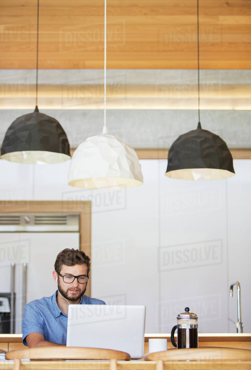 Man using laptop under pendant lights in kitchen - Royalty-free Stock ...