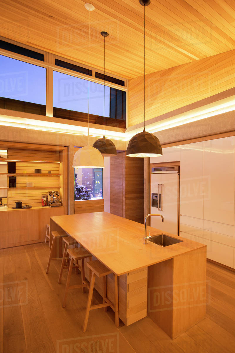 Illuminated slanted wood ceiling and pendant lights over kitchen island ...