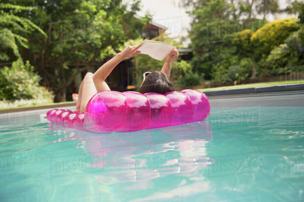 Woman reading book on inflatable raft in sunny summer swimming pool ...