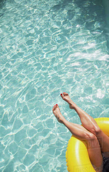 Woman with bare feet relaxing, floating in inflatable ring in sunny ...