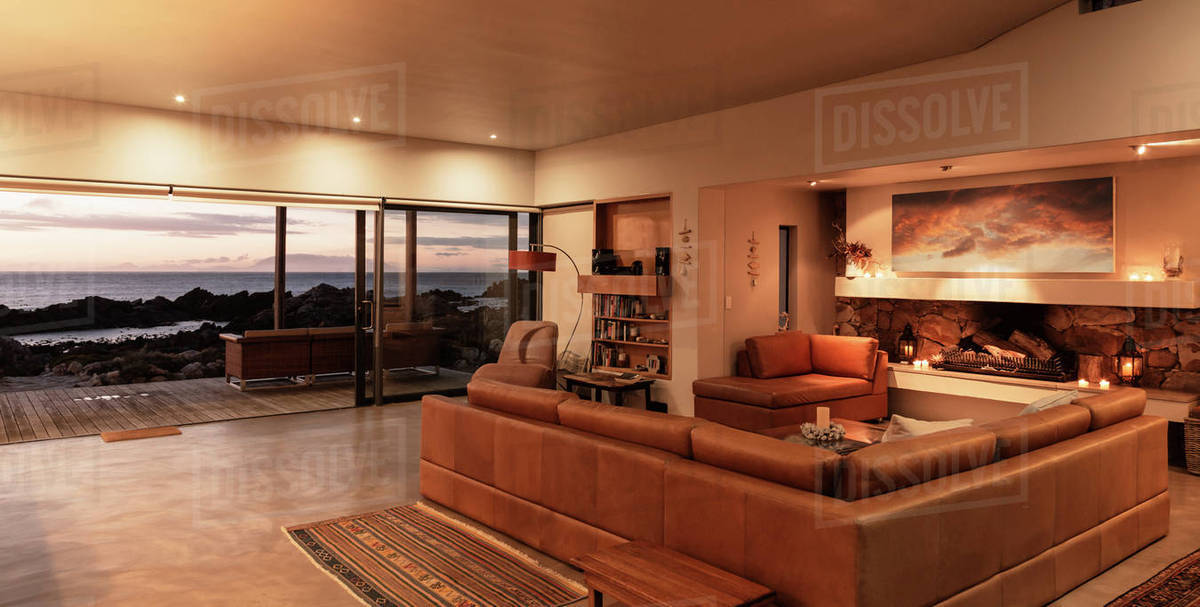 Home showcase interior living room overlooking ocean at sunset ...