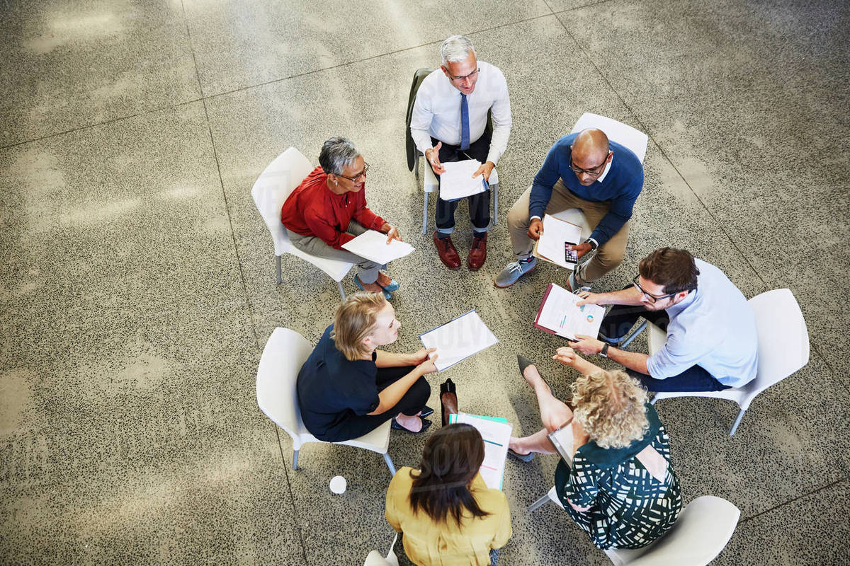 Business people discussing paperwork in meeting circle - Royalty-free ...