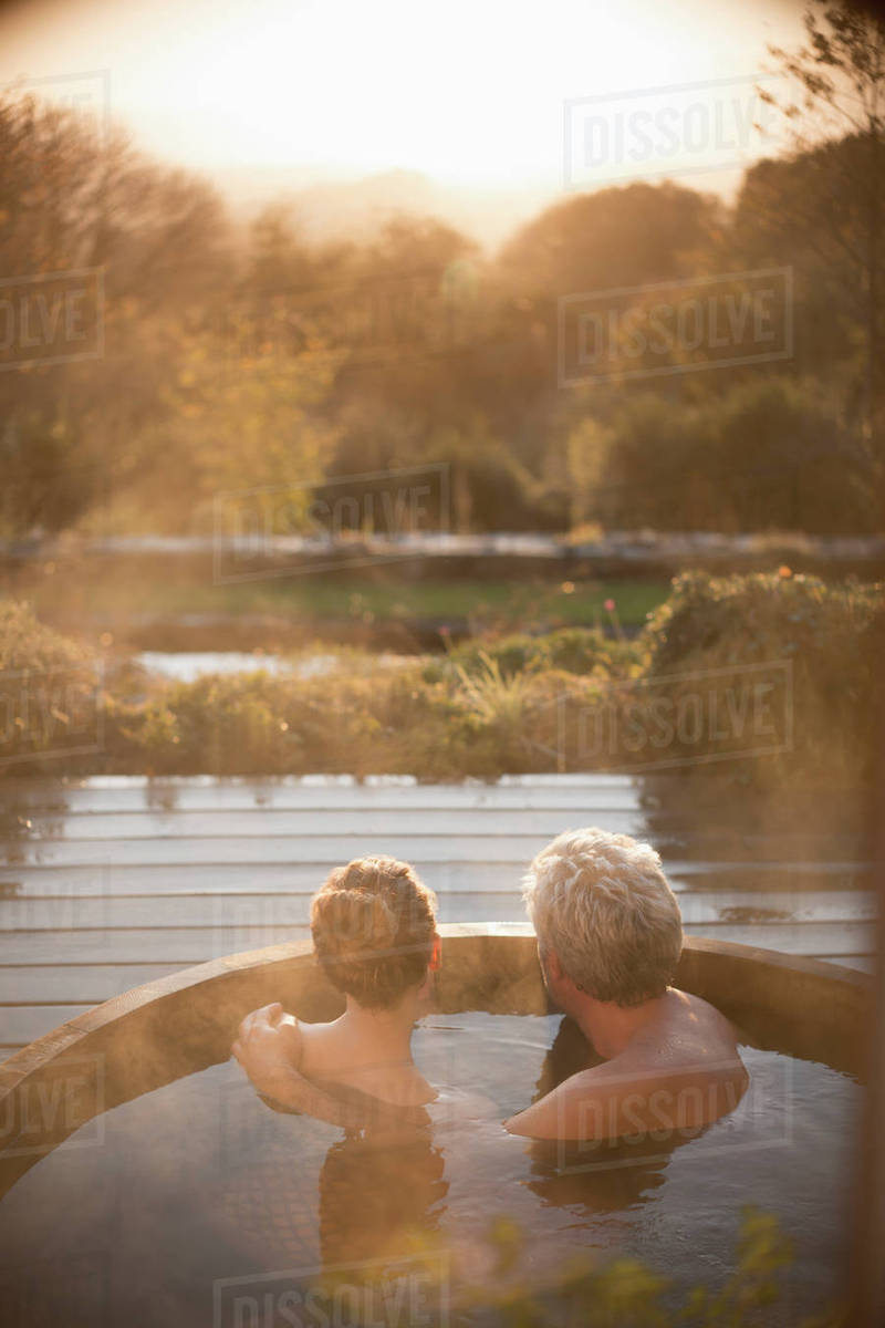 Serene affectionate couple soaking in hot tub on patio with autumn view ...