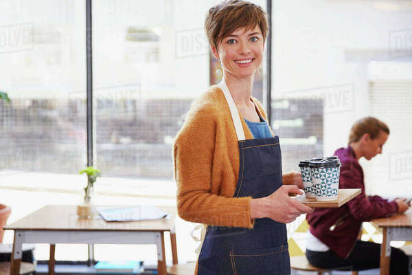 Portrait confident female cafe owner serving coffee on tray in cafe ...