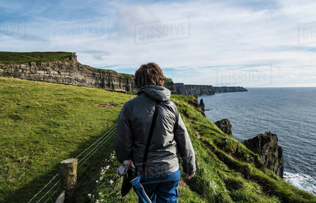 Ireland, County Clare, Woman walking along Cliffs of Moher - Royalty ...