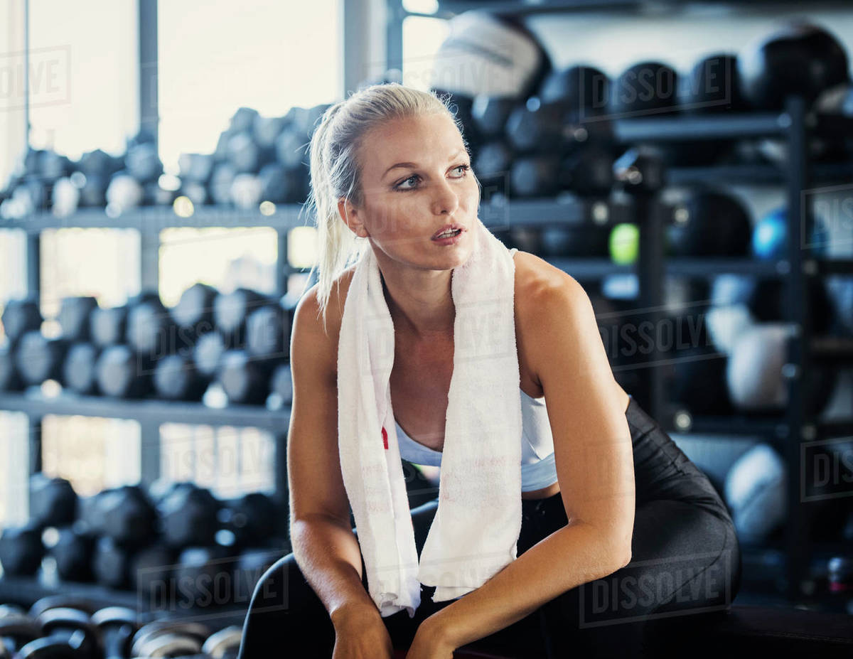 Young woman with towel in gym - Stock Photo - Dissolve