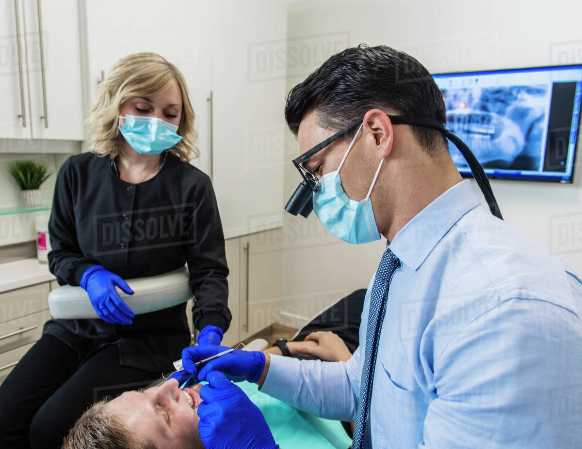 Dentist and dental nurse examining patient's teeth - Royalty-free Stock ...