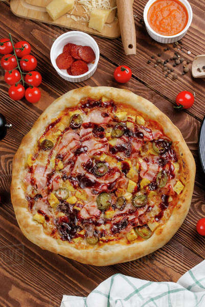 Pizza and ingredients on wooden table - Royalty-free Stock Photo | Dissolve