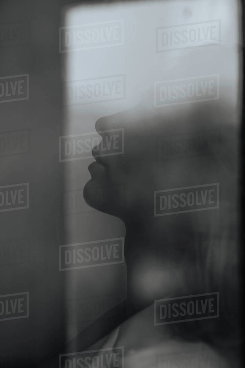 Profile of young woman behind window - Royalty-free Stock Photo | Dissolve