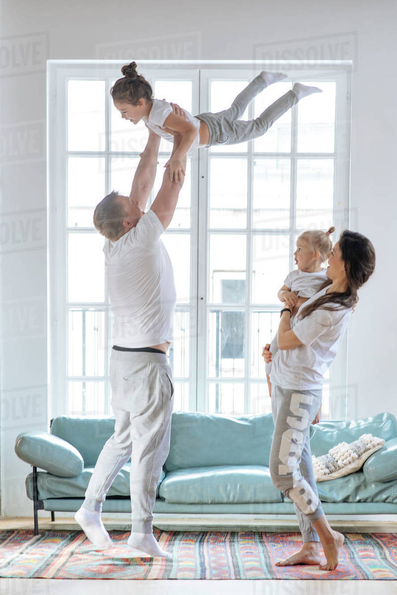 Parent lifting daughters by window - Stock Photo - Dissolve
