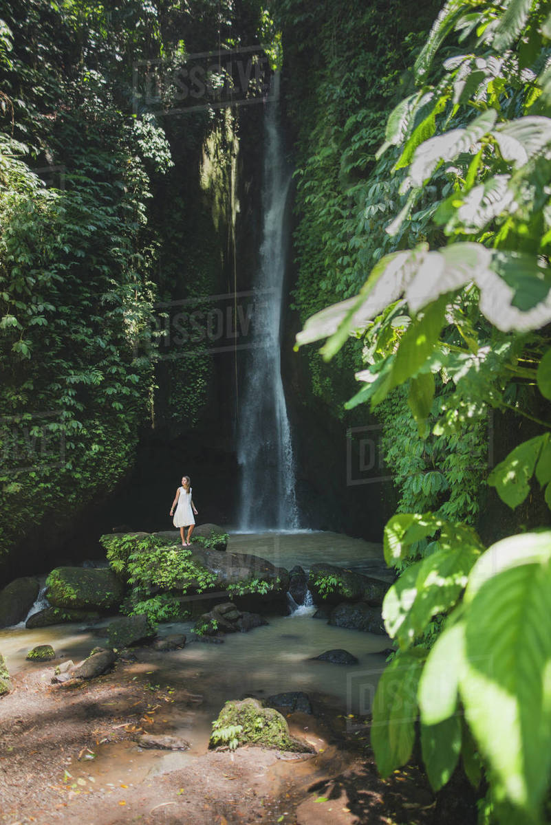 Woman by waterfall in Bali, Indonesia - Stock Photo - Dissolve