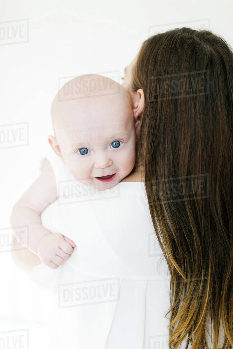 Baby boy looking over his mother's shoulder - Stock Photo - Dissolve