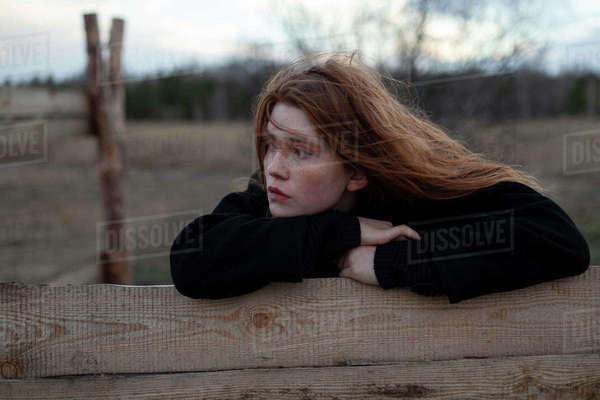 Teenage girl leaning on wooden fence - Royalty-free Stock Photo | Dissolve
