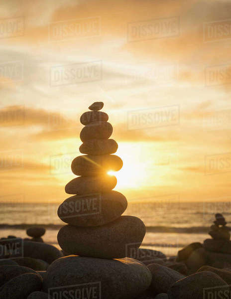 Stacked stones on beach at sunset - Royalty-free Stock Photo | Dissolve