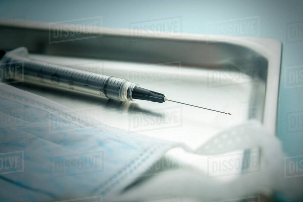 Needle and hygiene mask on tray - Stock Photo - Dissolve