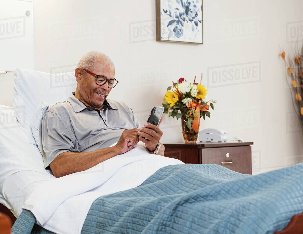 Senior man lying in bed and using smart phone - Royalty-free Stock ...