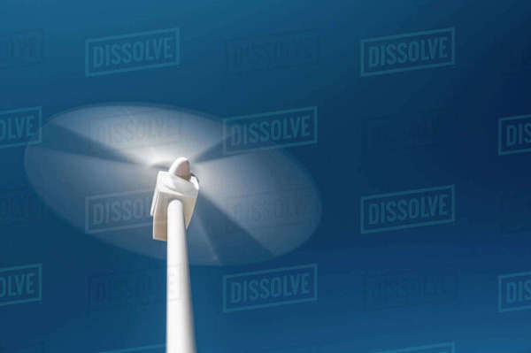 Low angle view of wind turbine spinning against blue sky - Stock Photo ...