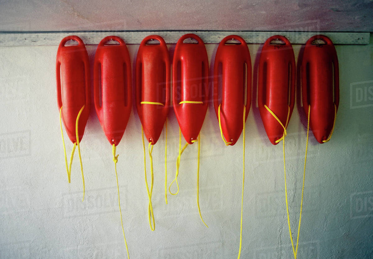 Row of red lifeguard floats hanging on wall - Stock Photo - Dissolve