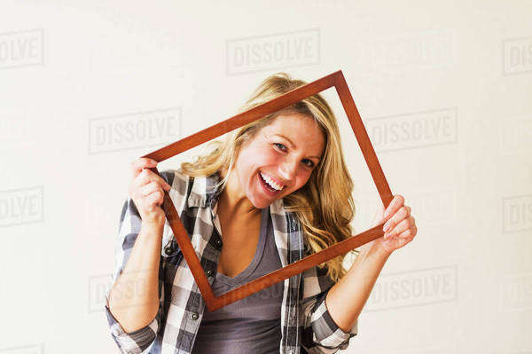 Portrait of woman holding picture frame - Stock Photo - Dissolve