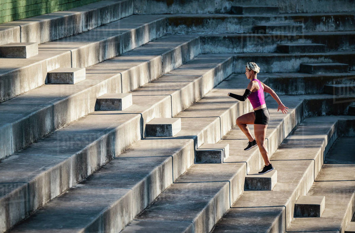 Athletic woman with amputated hand running up steps - Stock Photo ...
