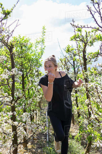 Teenage girl (16-17) walking between vines growing in vineyard ...