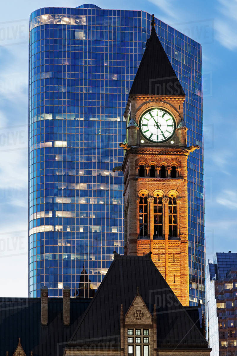 Illuminated clock tower and skyscraper at sunrise - Stock Photo - Dissolve