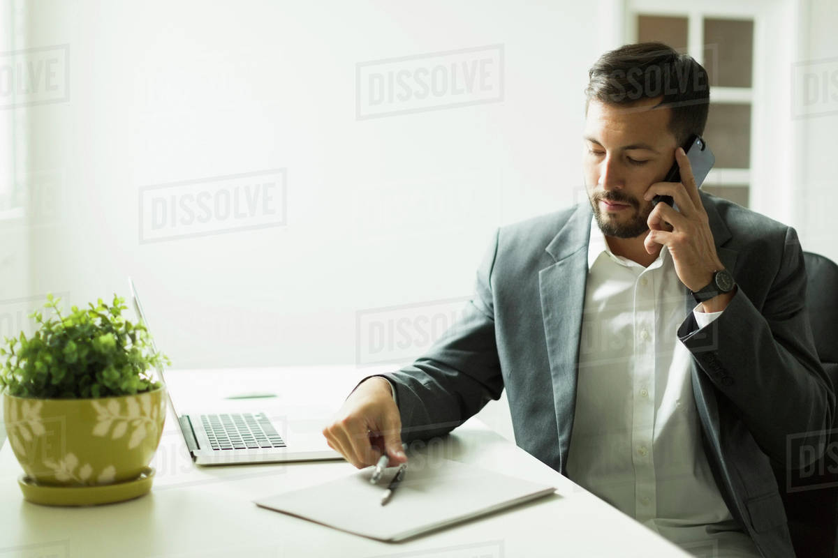 Young man sitting at desk and looking at laptop - Royalty-free Stock ...