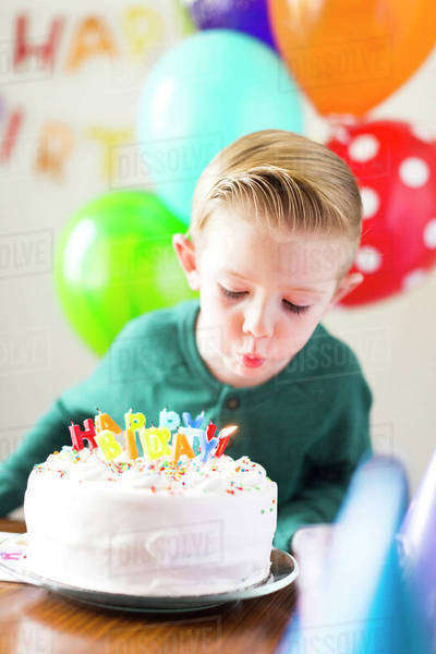 Boy (2-3) blowing out candles - Stock Photo - Dissolve
