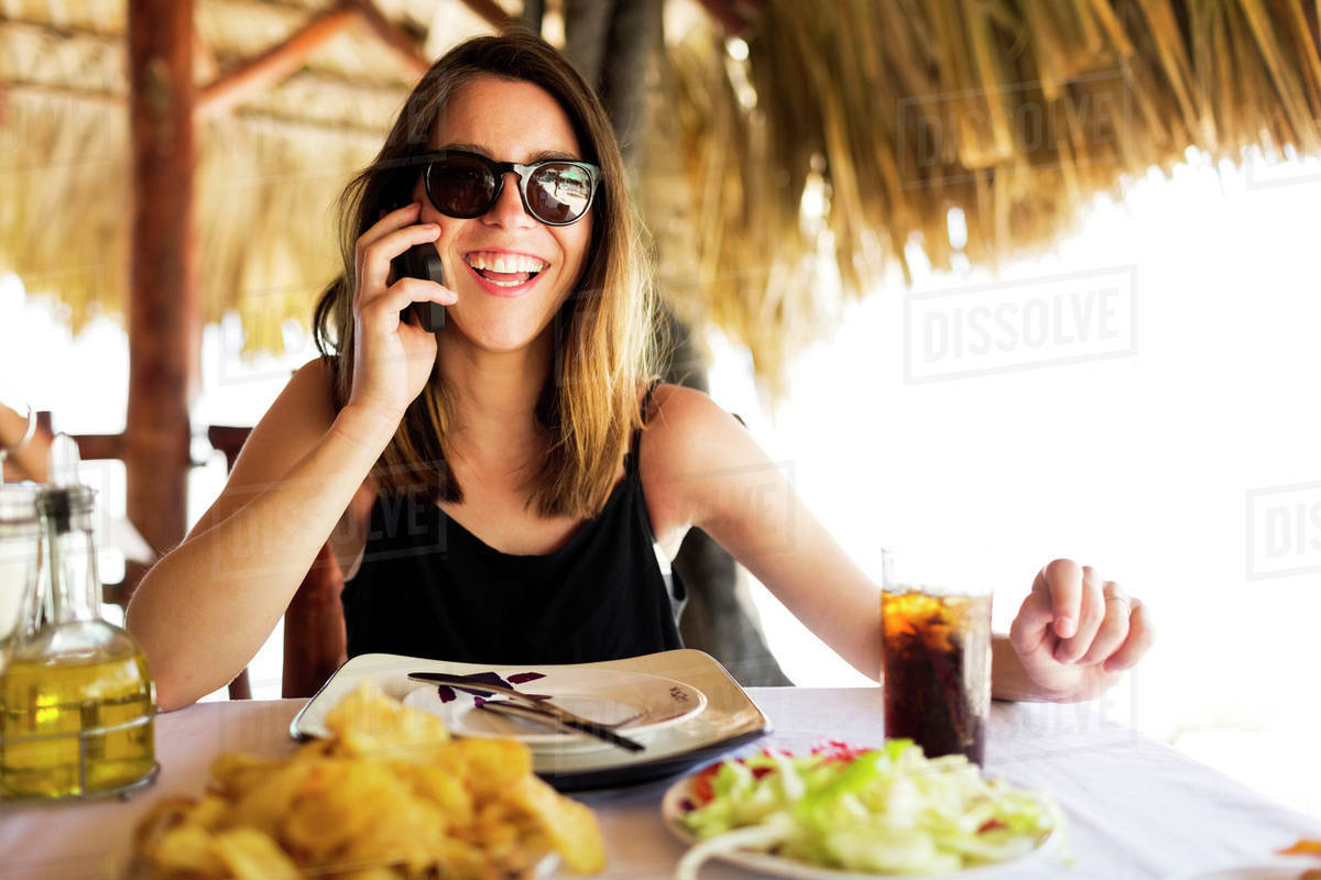 Woman by table, using phone - Stock Photo - Dissolve