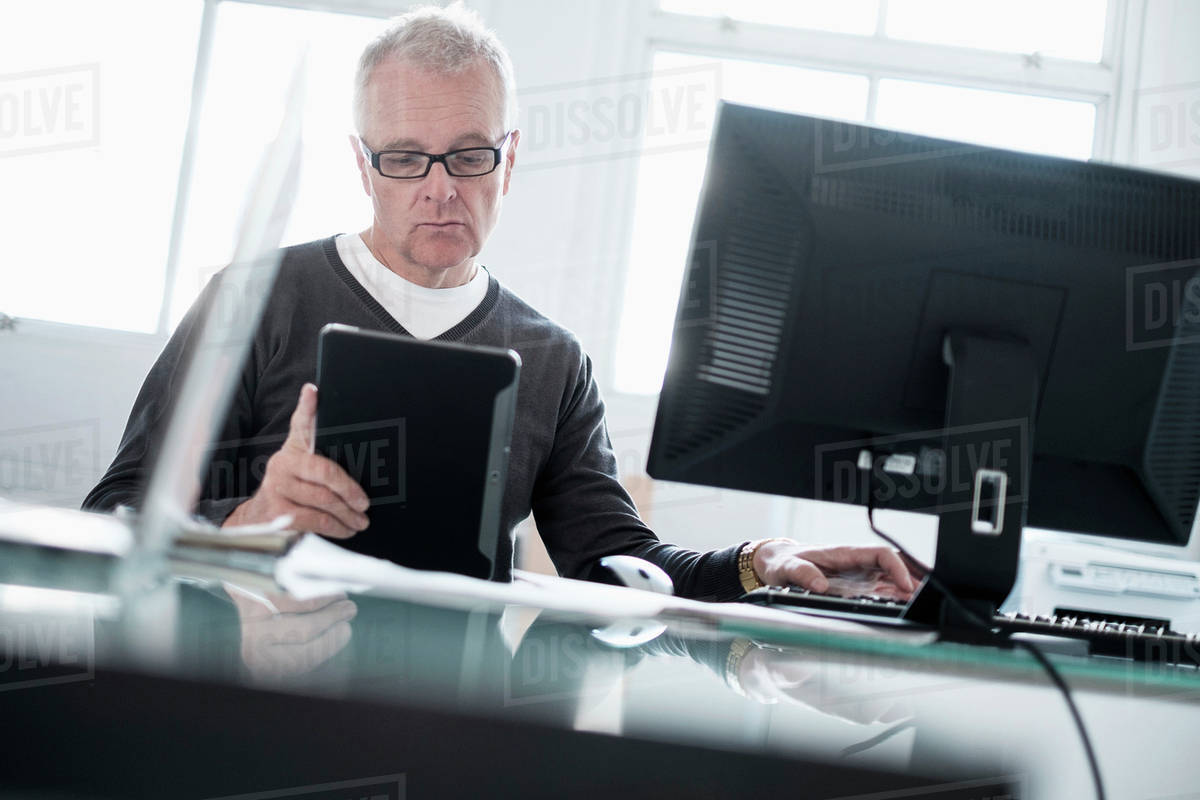 Man working in office using computer and tablet - Royalty-free Stock ...