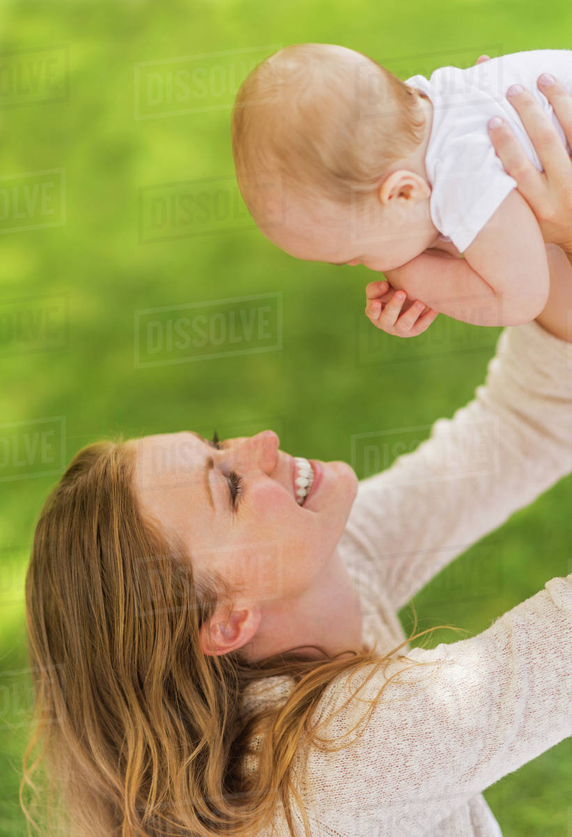 Mother holding up baby boy (6-11 months) - Stock Photo - Dissolve