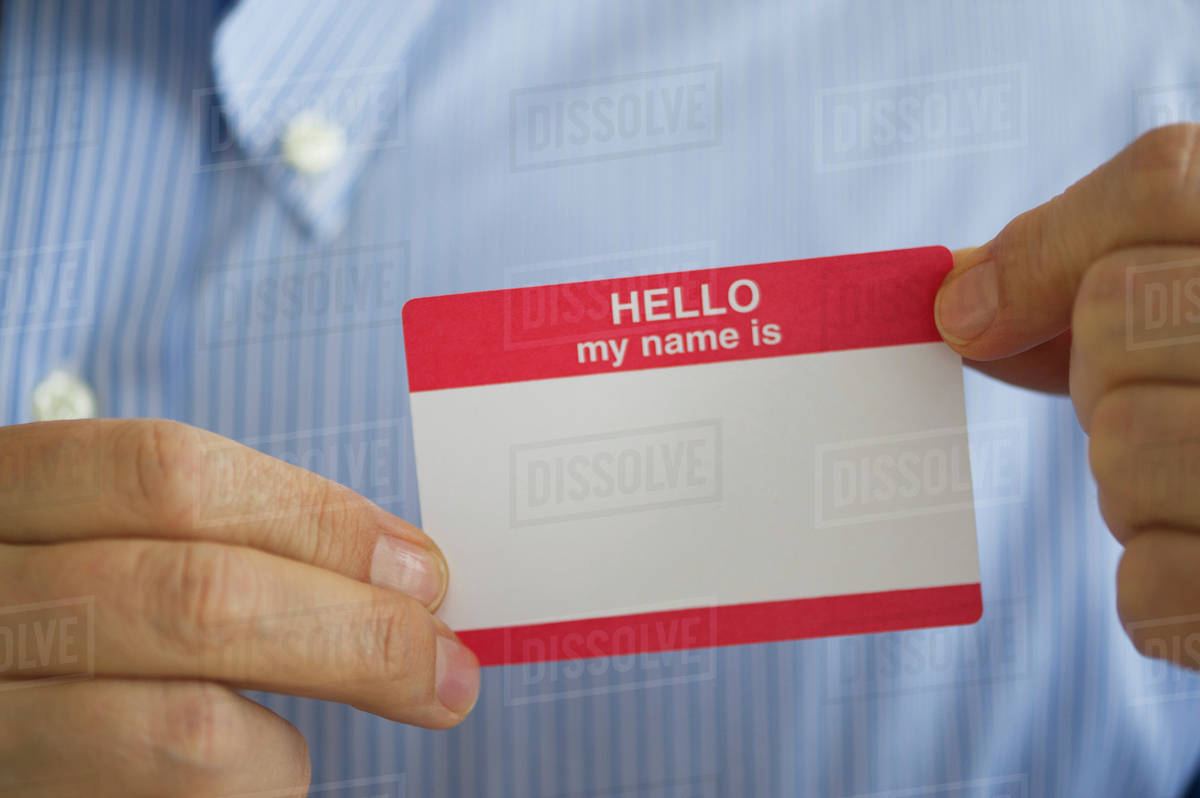 Close up of businessman's hands holding blank name tag, studio shot ...