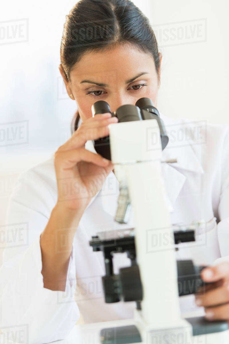 Female scientist looking through microscope - Royalty-free Stock Photo ...