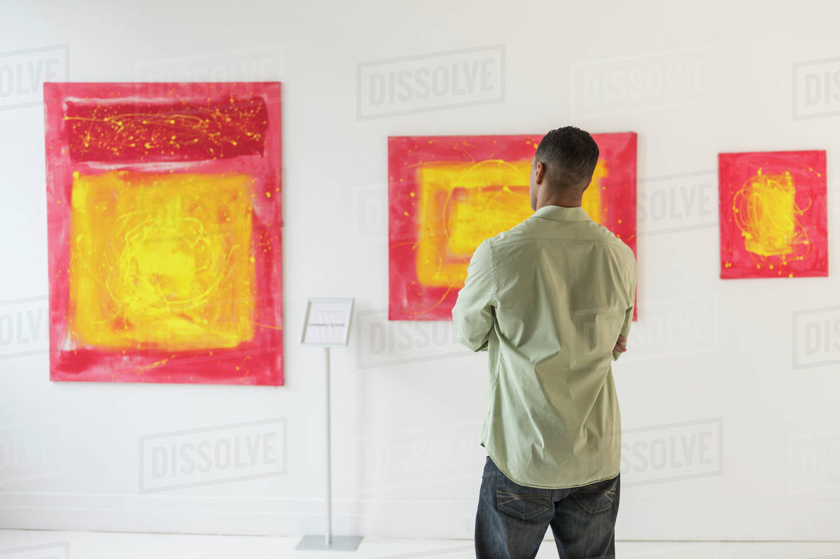 Man watching paintings in modern art gallery - Stock Photo - Dissolve