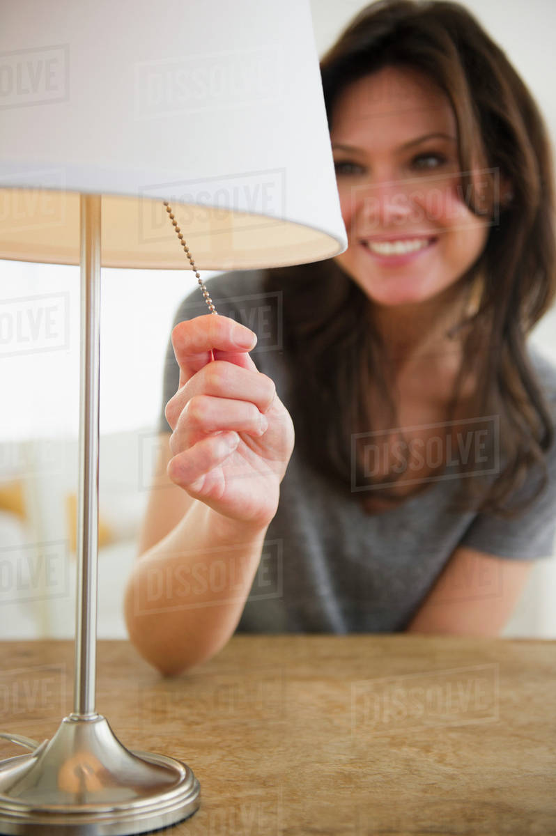 Woman pulling lamp switch - Royalty-free Stock Photo | Dissolve