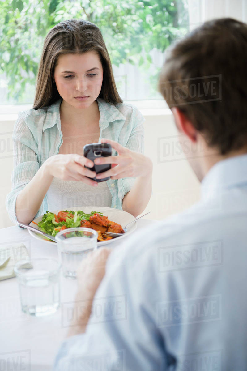 Yung woman texting over meal - Royalty-free Stock Photo | Dissolve