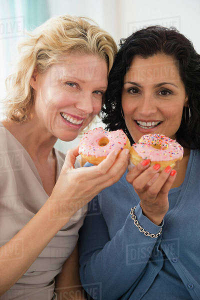 Female friends eating donuts - Stock Photo - Dissolve